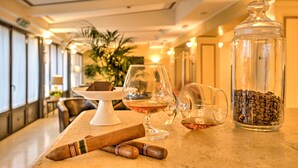Uma área de bar com uma taça de vinho, um charuto, um copo e um pote de grãos de café.