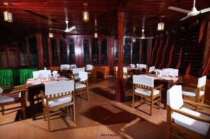 Um restaurante com móveis de madeira, mesas com toalhas brancas e ventiladores de teto.