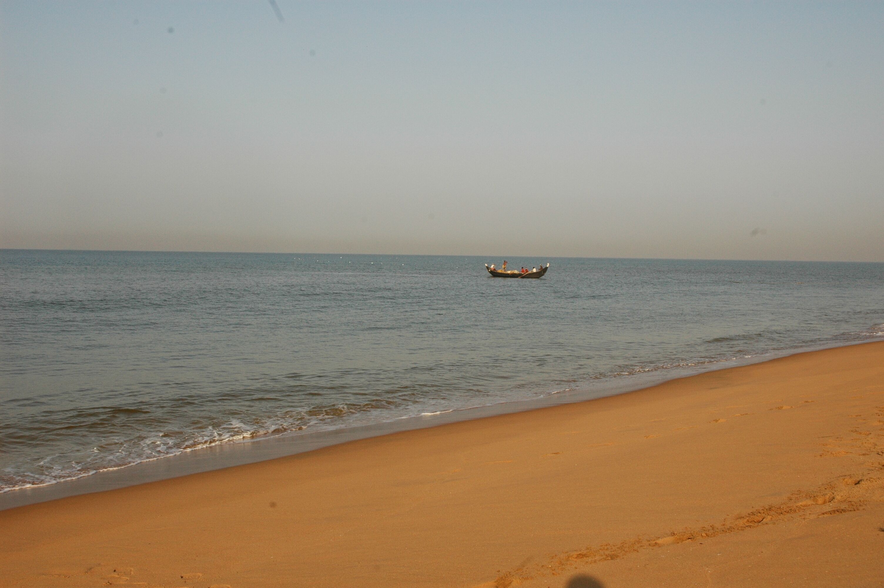 Uma praia com um barco na água e uma faixa de areia.