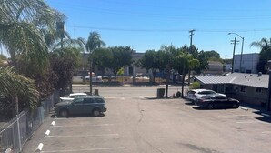 Um estacionamento com vários carros, uma cerca e edifícios ao fundo.