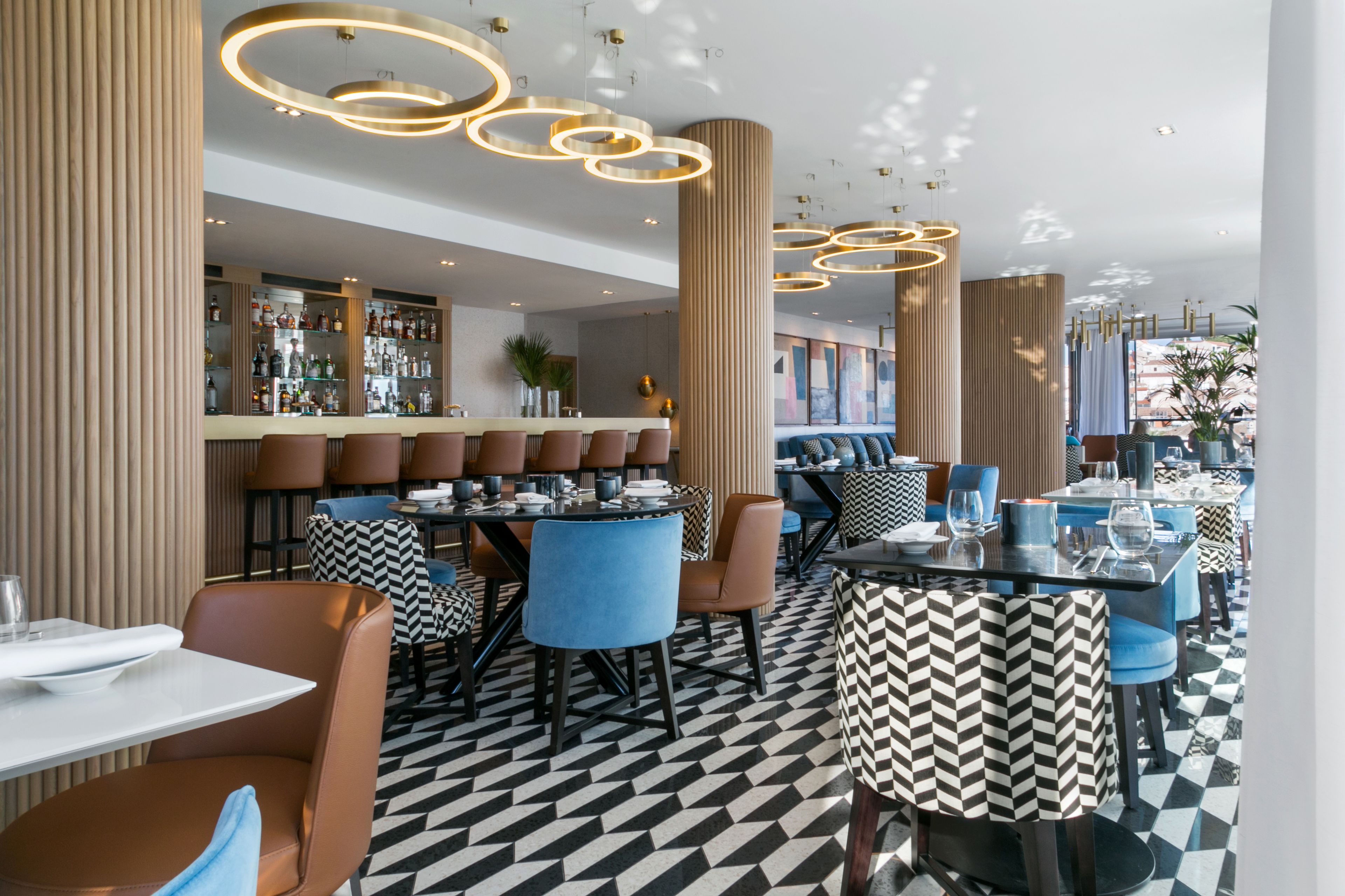 Restaurante moderno com área de bar, piso com padrão preto e branco e luminárias contemporâneas.
