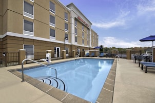 Um hotel com piscina, área de estar externa e céu claro.