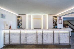 Uma área de recepção com balcão de mármore, uma placa com a inscrição 