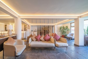 Um lobby moderno com um conjunto de sofás, um balcão de recepção e uma escadaria.