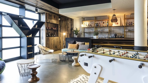 Uma sala de estar moderna com mesa de bilhar, detalhes em madeira e um espaço bar com prateleiras cheias de garrafas e copos.