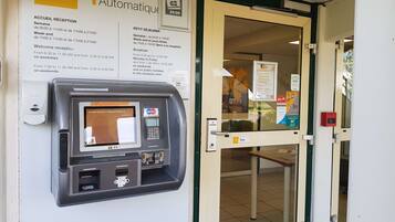 Uma área de recepção de hotel com um balcão de atendimento automático 24 horas por dia, um terminal de check-in automático e entrada por porta de vidro.