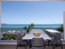Um terraço com mesa, cadeiras, uma fruteira e vista para o mar.