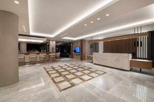 Um lobby moderno com balcão de recepção, área de estar e bar.