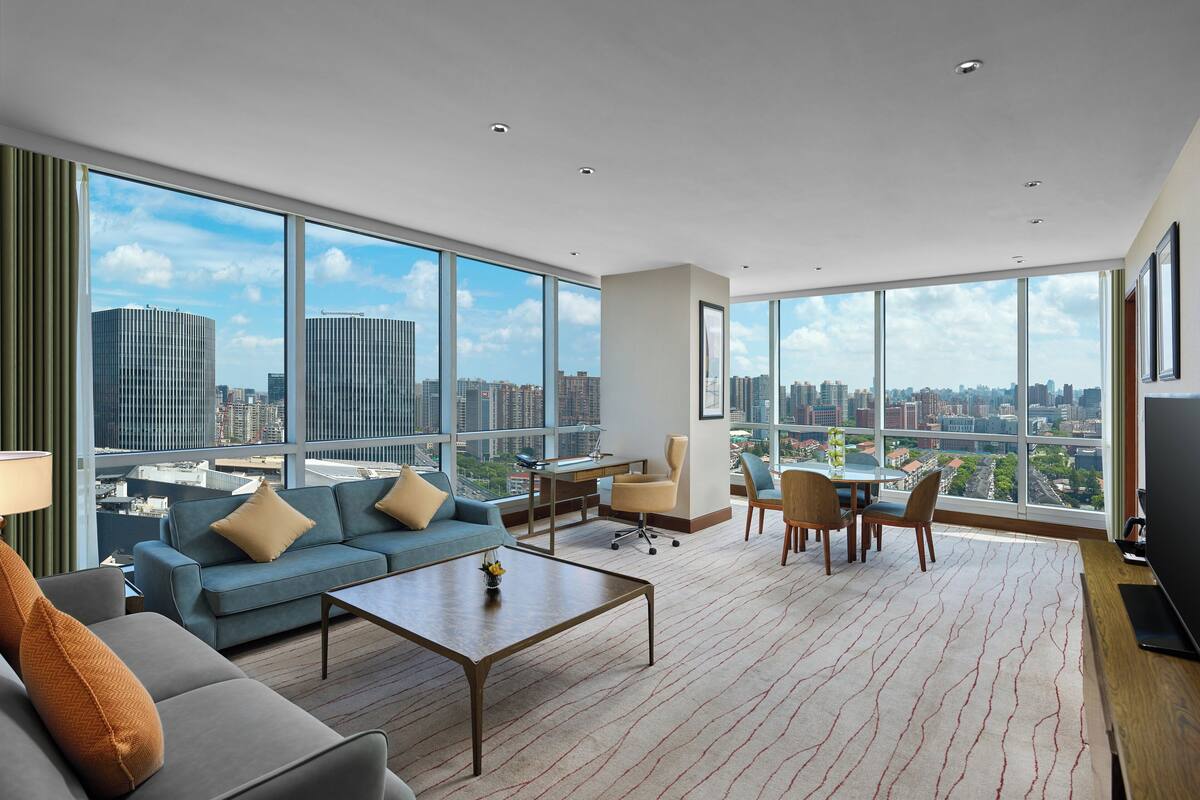 Sala de estar moderna com vista para a cidade, equipada com sofá, mesa de centro e cadeiras.