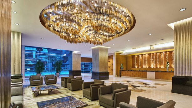 Um hall amplo com um grande candelabro, assentos confortáveis e uma área de recepção.