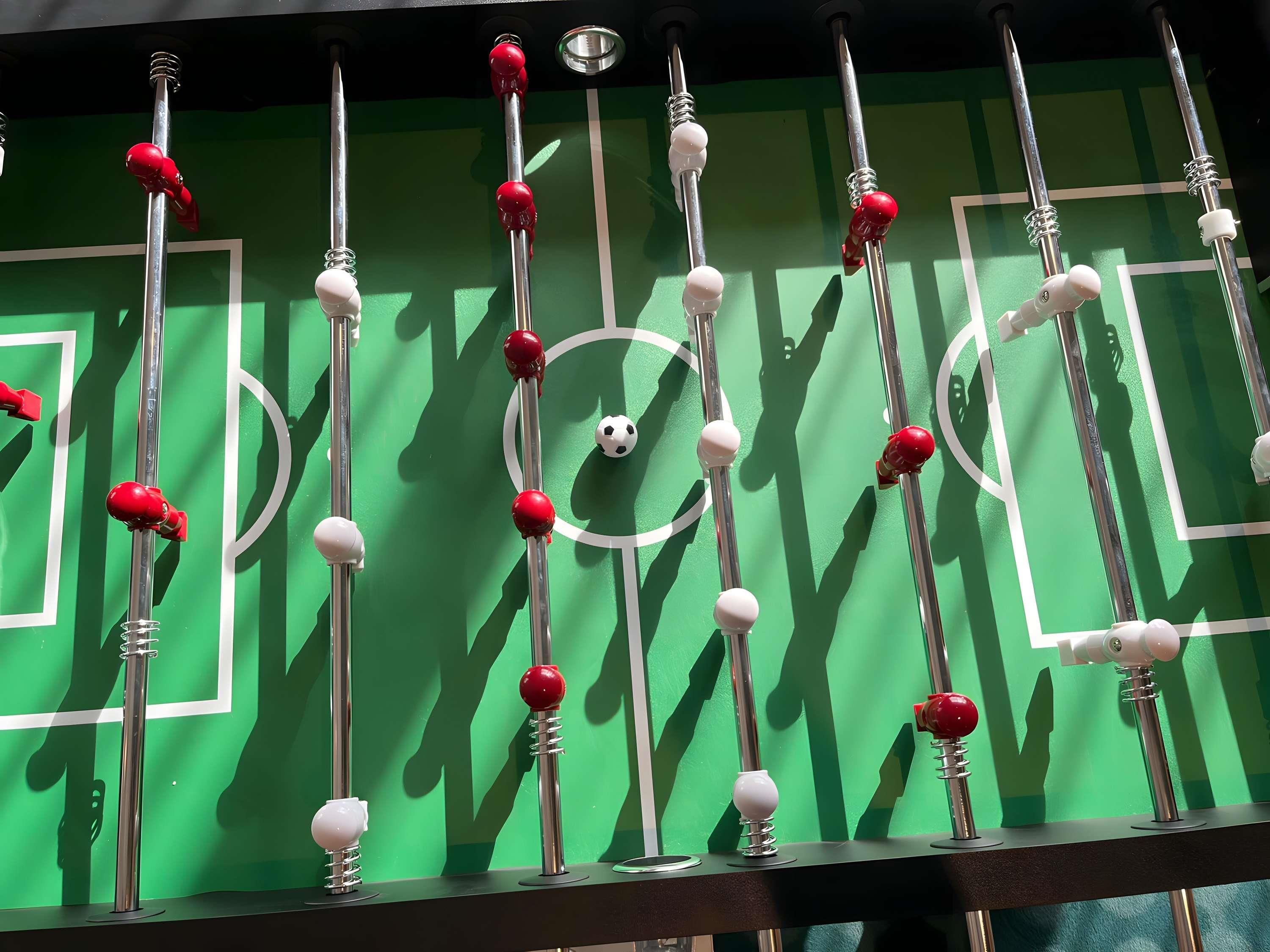 Uma mesa com superfície verde e linhas brancas que lembram um campo de futebol.
