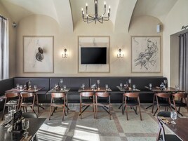 Um restaurante com um amplo banco, mesas com cadeiras e um candelabro.