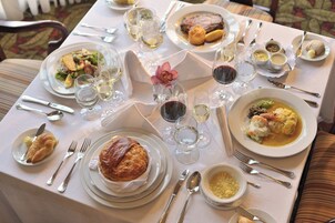 Uma mesa de jantar posta com diversos pratos, copos de vinho e talheres.