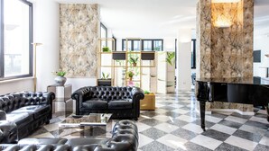 Uma sala de estar moderna com um sofá de couro preto, uma mesa de centro de vidro, um piano preto e um chão xadrez.