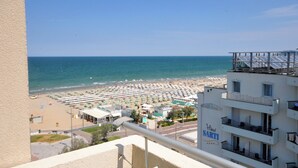 Hotel Sartti, com vista para uma praia com vários guarda-sóis e espreguiçadeiras.