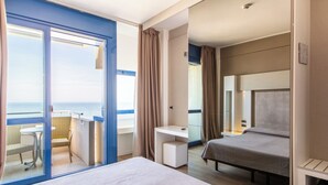 Quarto de hotel com varanda, cama, escrivaninha e uma cadeira.
