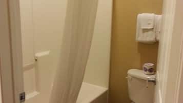 Um banheiro com banheira, cortina de chuveiro, vaso sanitário e porta-toalhas.