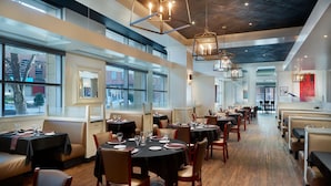 Um restaurante espaçoso com diversas áreas de refeições, grandes janelas e luminárias modernas.