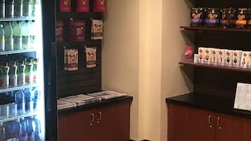Uma área de distribuição automática com máquina de Coca-Cola Zero, embalagens de snack e água engarrafada.