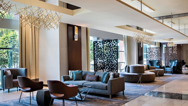 Um lobby moderno com um conjunto de sofás, cadeiras e uma mesa de centro.
