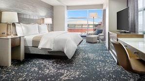 Quarto de hotel com cama, escrivaninha, cadeira, televisão e vista para a praia.