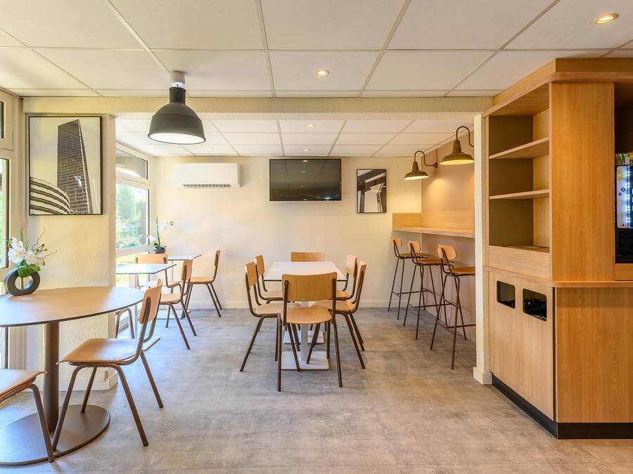 Um café moderno com um balcão extenso, várias mesas e cadeiras.