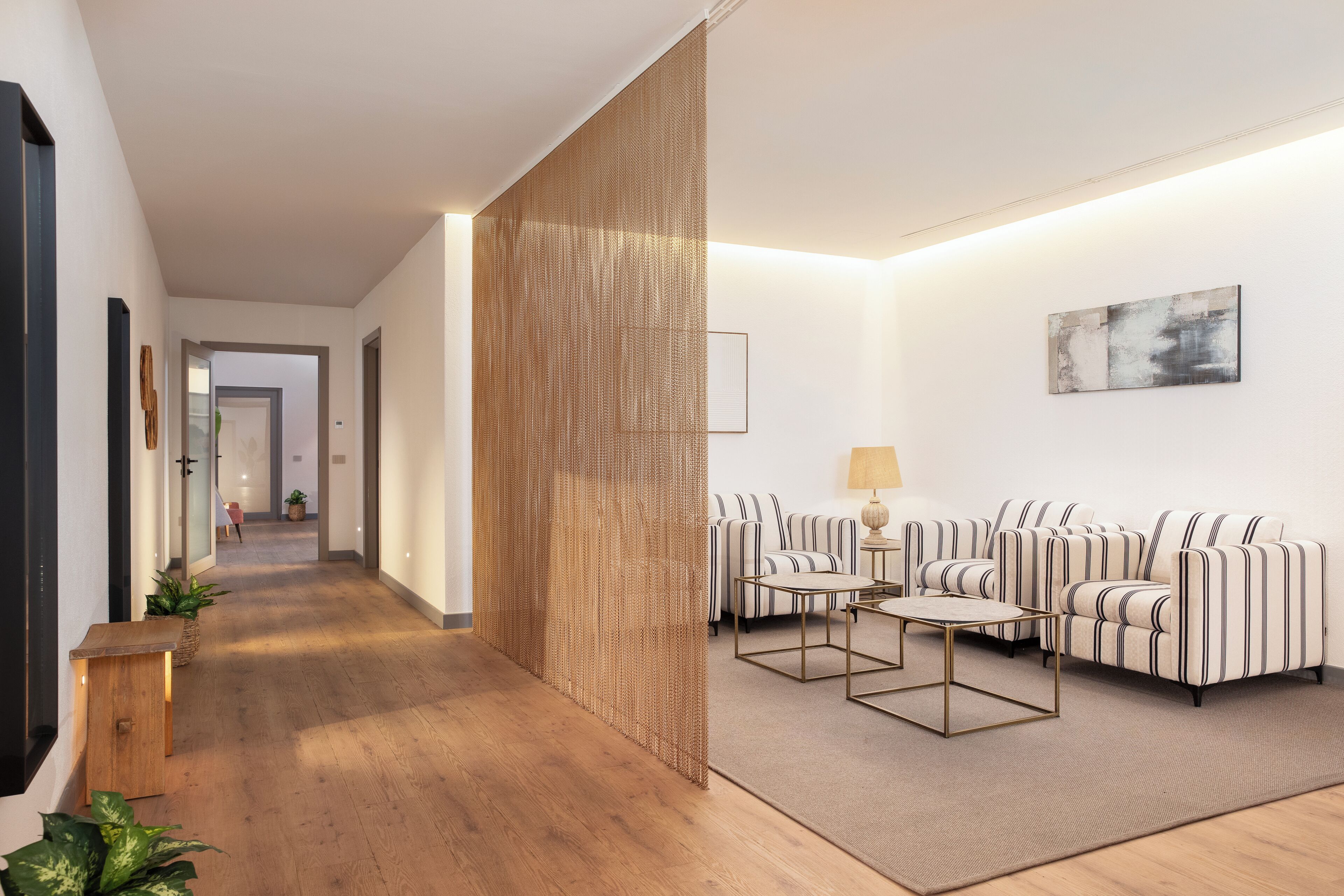 Uma sala de estar moderna com sofás listrados, uma mesa de centro e um biombo decorativo.