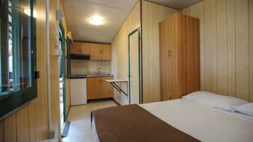 Quarto compacto com uma cama, uma kitchenette pequena e paredes de madeira.