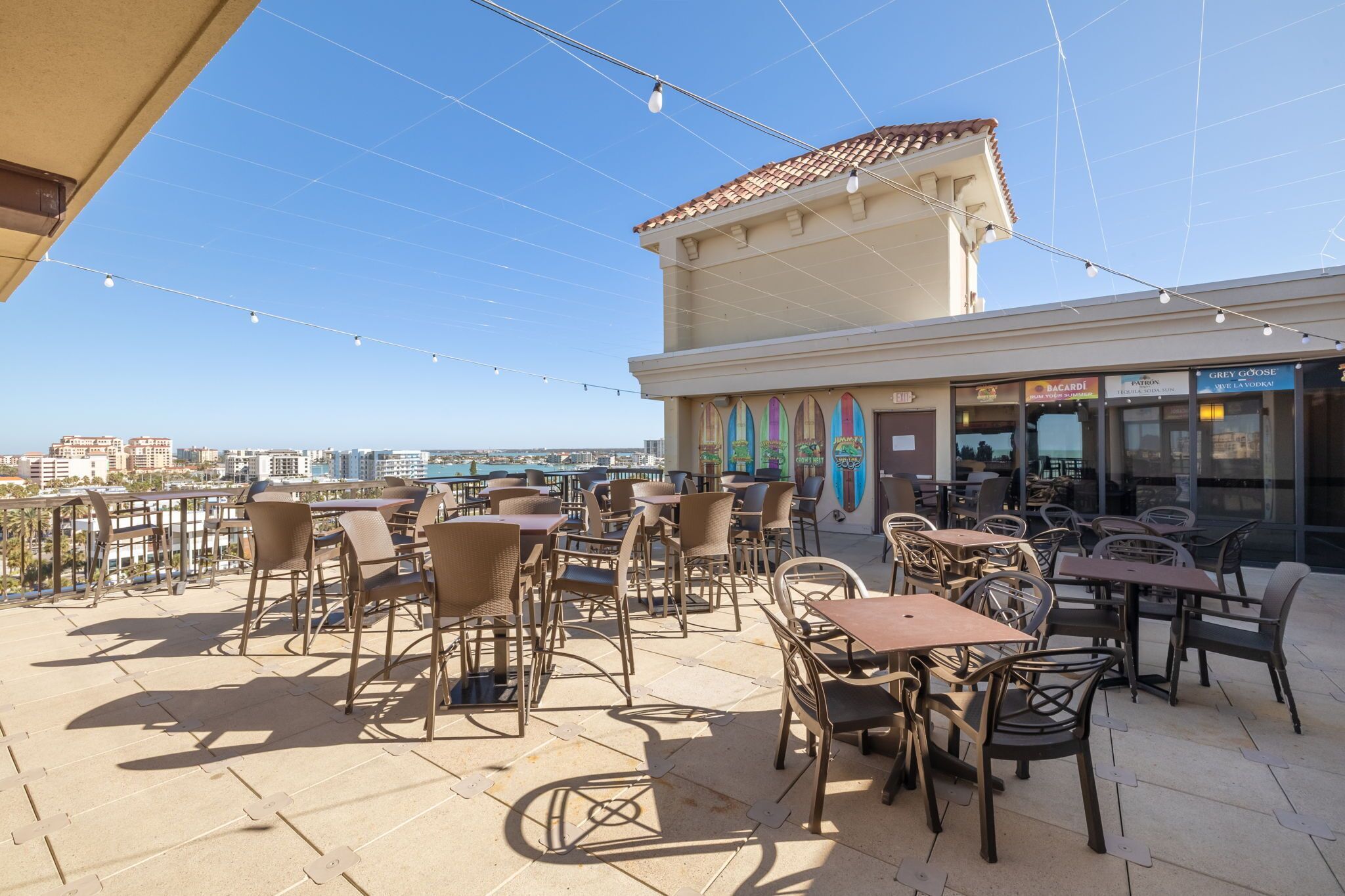 Um café ao ar livre com mesas e cadeiras, piso de azulejos e vista para a cidade.