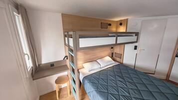 Quarto com beliche, escrivaninha, cadeira, guarda-roupa e janela.