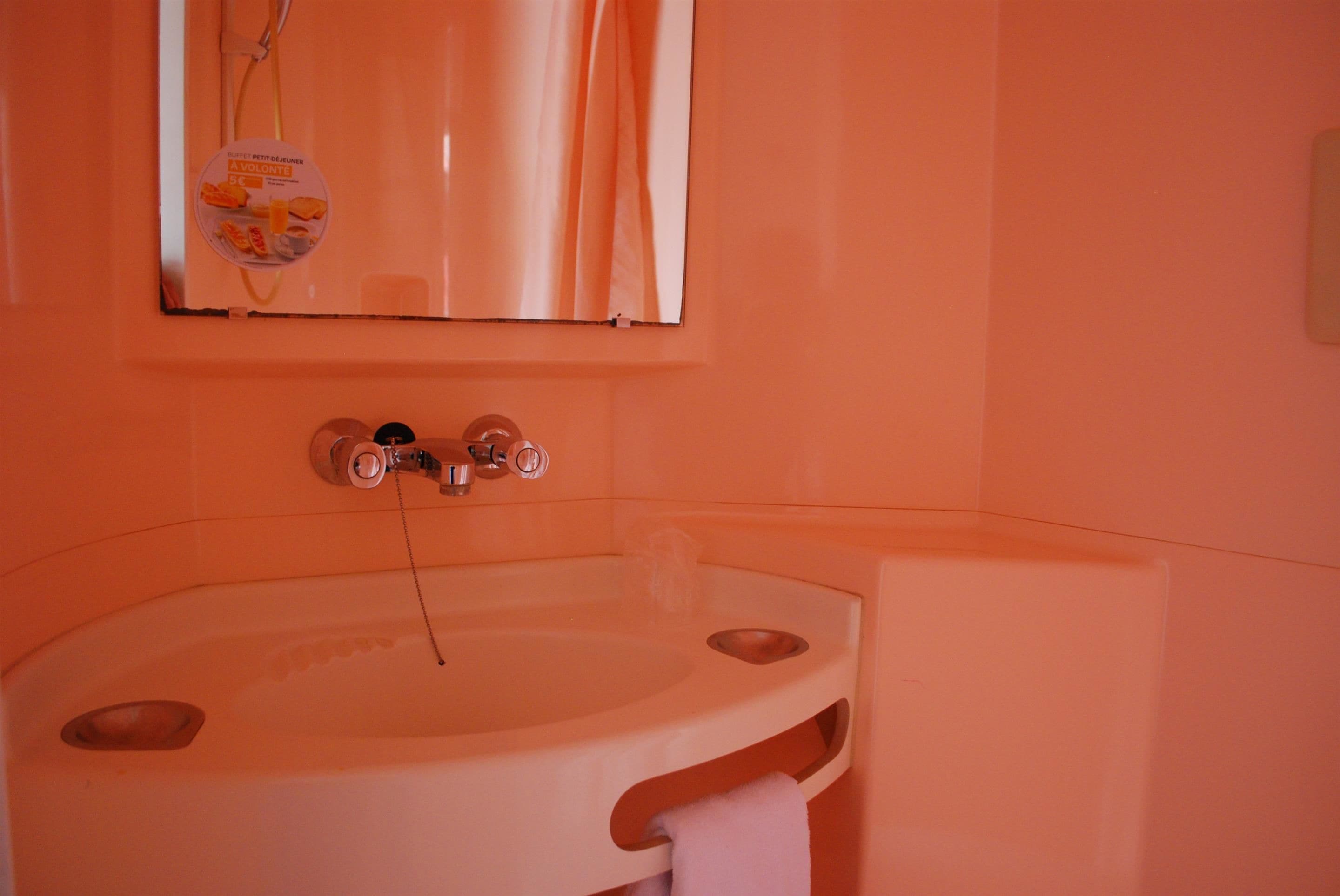 Casa de banho com lavatório, espelho e porta-toalhas.