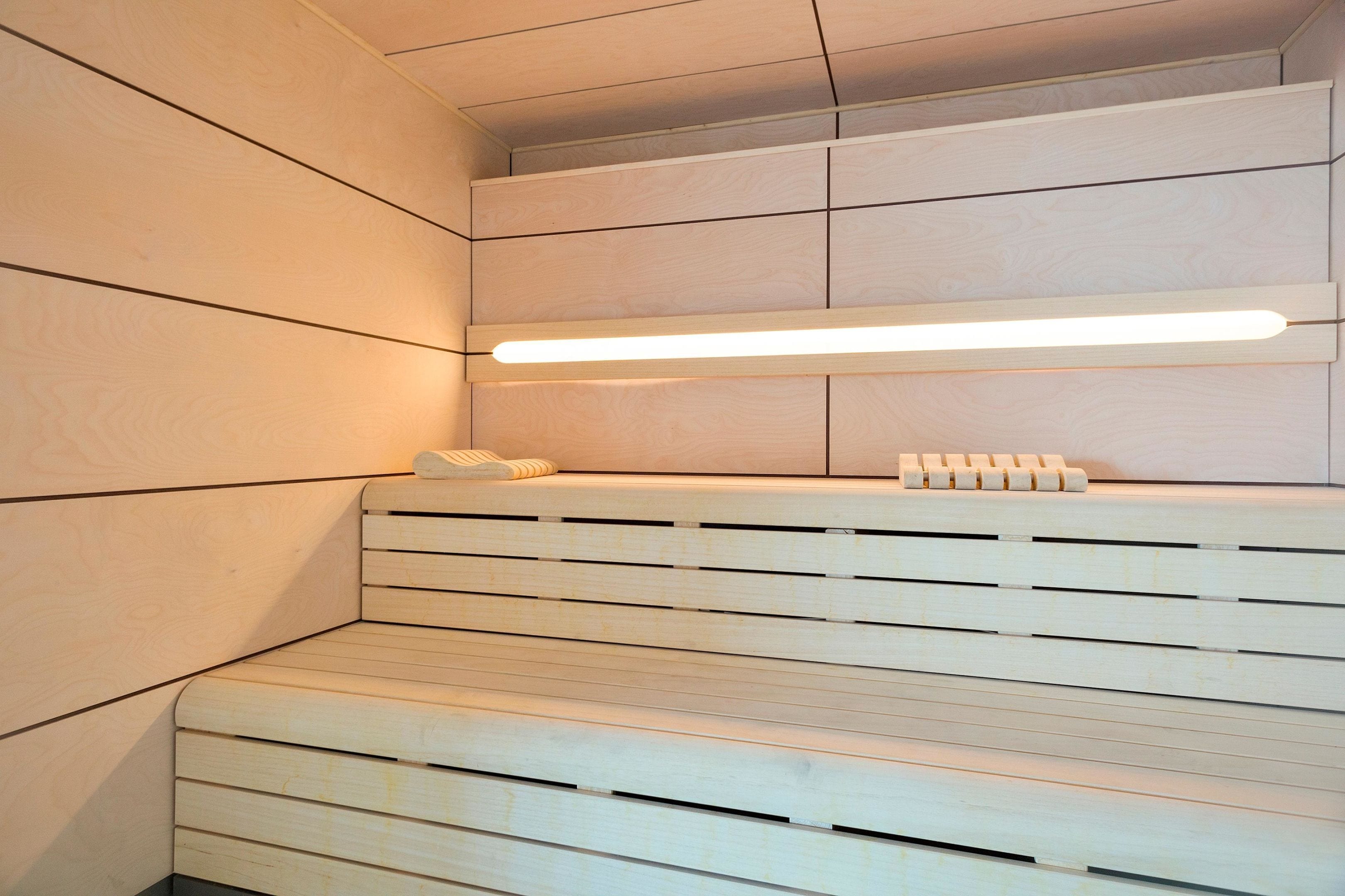 Casa de banho moderna e minimalista, com painéis de madeira e iluminação linear.