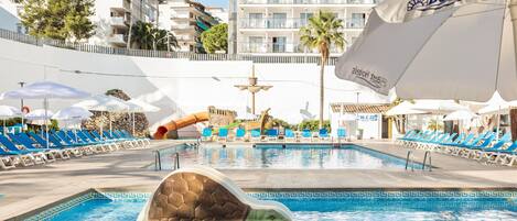 Uma área de piscina de hotel com várias espreguiçadeiras, um toboágua e um grande guarda-sol.