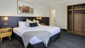Quarto de hotel com cama, mesas de cabeceira, guarda-roupa e um quadro na parede.