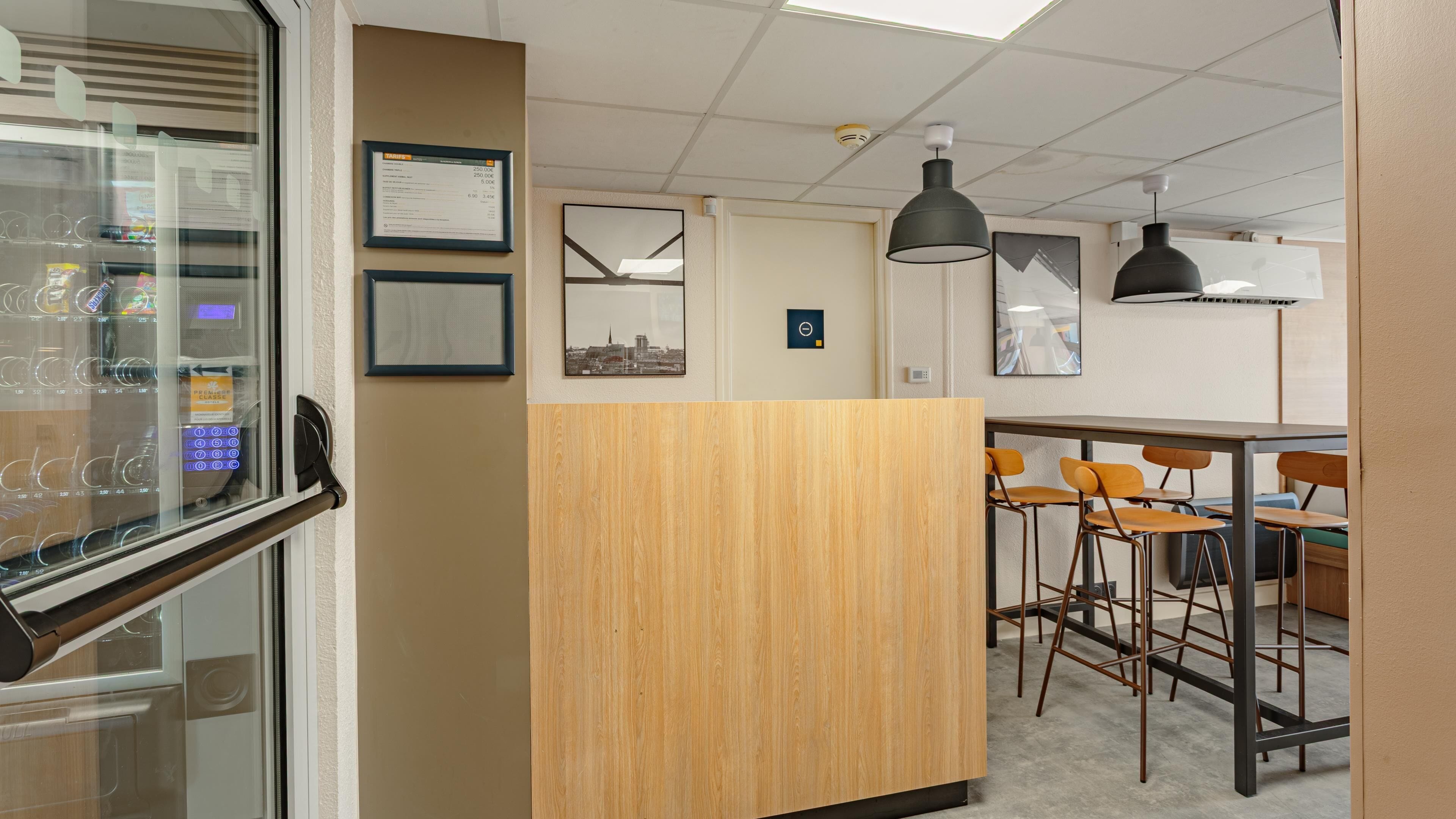Um espaço de escritório moderno com uma receção em madeira, obras de arte com a paisagem urbana emoldurada e uma área de bar com banquetas.