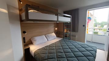 Quarto de hotel moderno com beliche, uma mesa de trabalho e varanda com vista.
