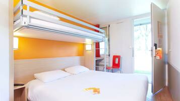 Quarto de hotel com beliche, uma escrivaninha, uma cadeira e porta para área externa.
