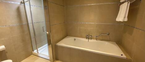 Um banheiro moderno com chuveiro em box de vidro, banheira de pedestal e porta-toalhas.