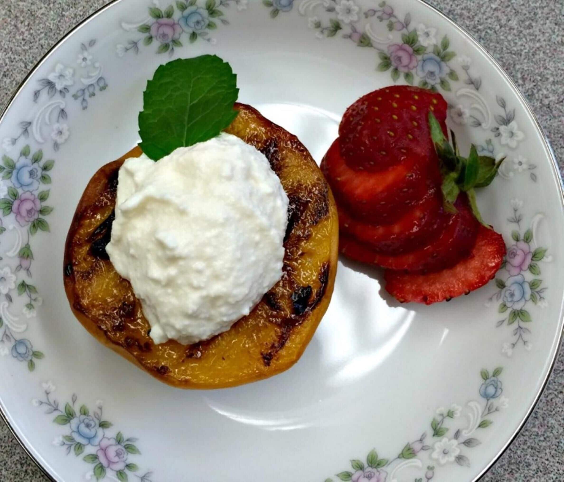 Uma fatia de pêssego grelhado com chantilly e morango.