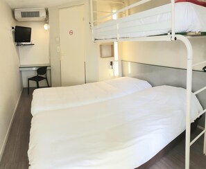 Quarto com beliche, escrivaninha, cadeira, televisão e aviso de proibido fumar.