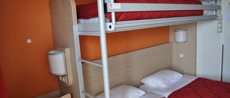 Uma cama beliche com um cobertor vermelho, um travesseiro branco e um encosto de madeira.