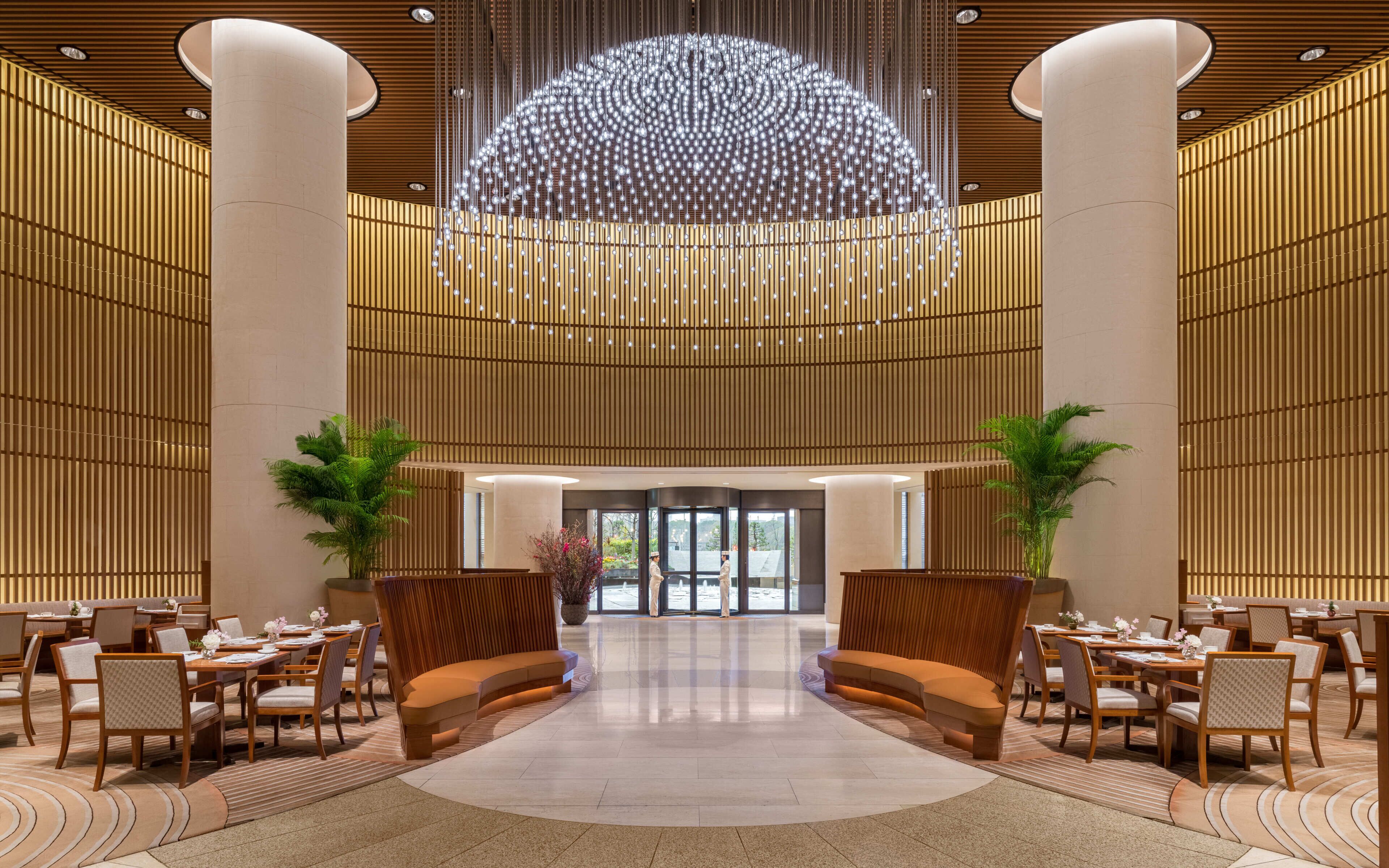Um hall amplo com área de estar central, um lustre grande e design moderno.