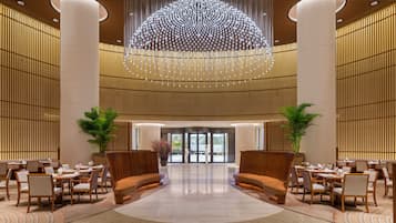 Um hall amplo com área de estar central, um lustre grande e design moderno.