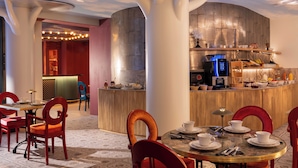 Um restaurante com decoração moderna, apresentando um espaço de bar, mesas e cadeiras.