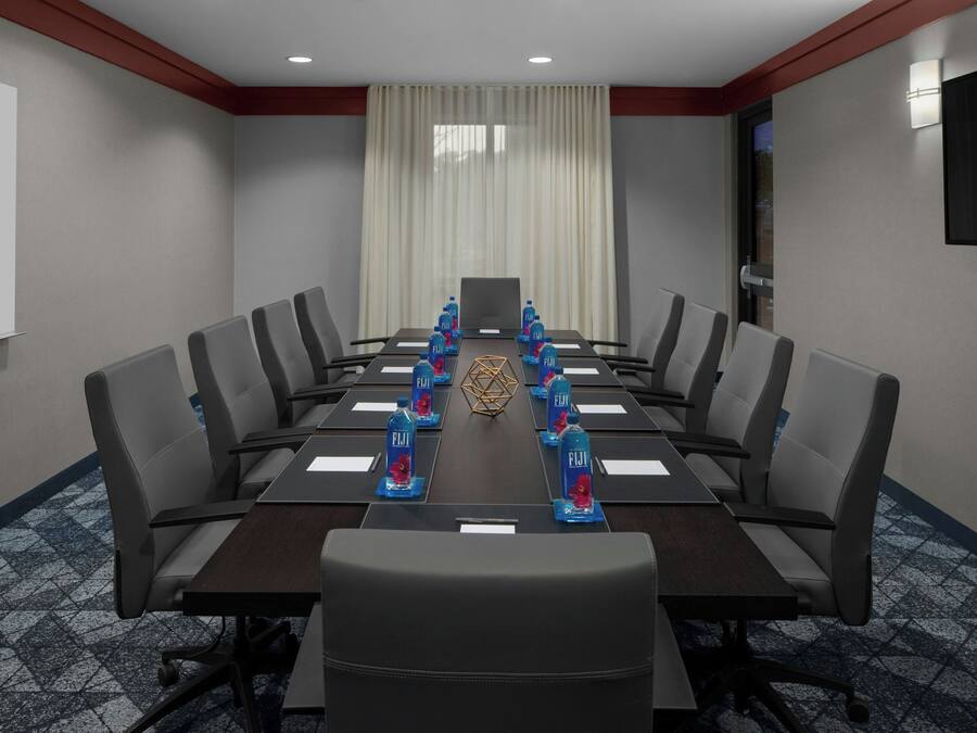 Uma sala de conferência com uma mesa comprida, cadeiras e garrafas de água com a etiqueta "FIJI".