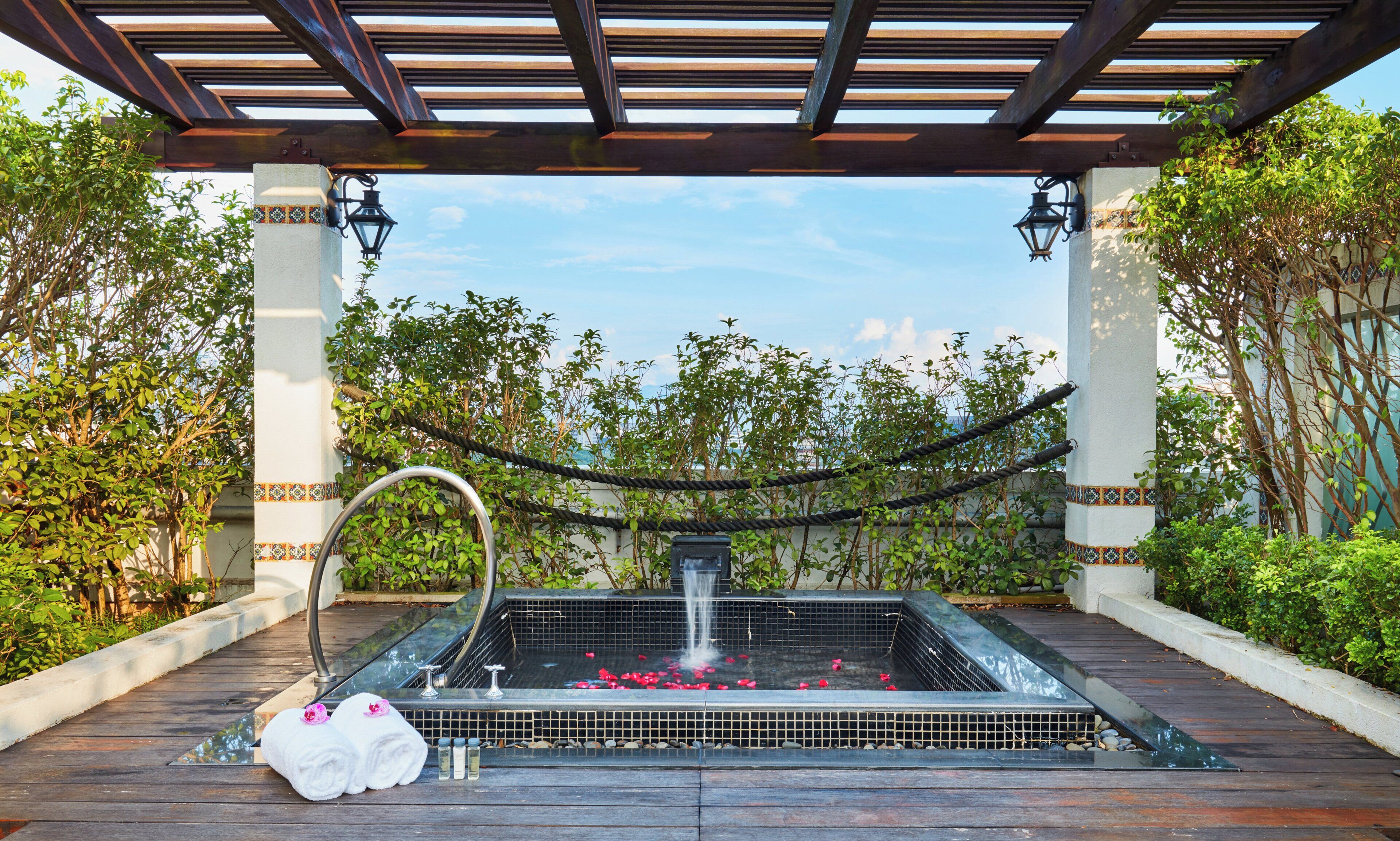 Área de spa com hidromassagem, deck de madeira e vegetação ao redor.