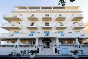 Um hotel com vários andares, entrada imponente, varandas e uma placa com a inscrição 'TERRAZZA MARCONI'.
