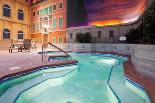 Piscina interna com mural de pôr do sol, área de estar com cadeiras e parede de pedra.