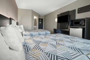 Quarto de hotel com duas camas, uma escrivaninha, uma televisão e um micro-ondas.