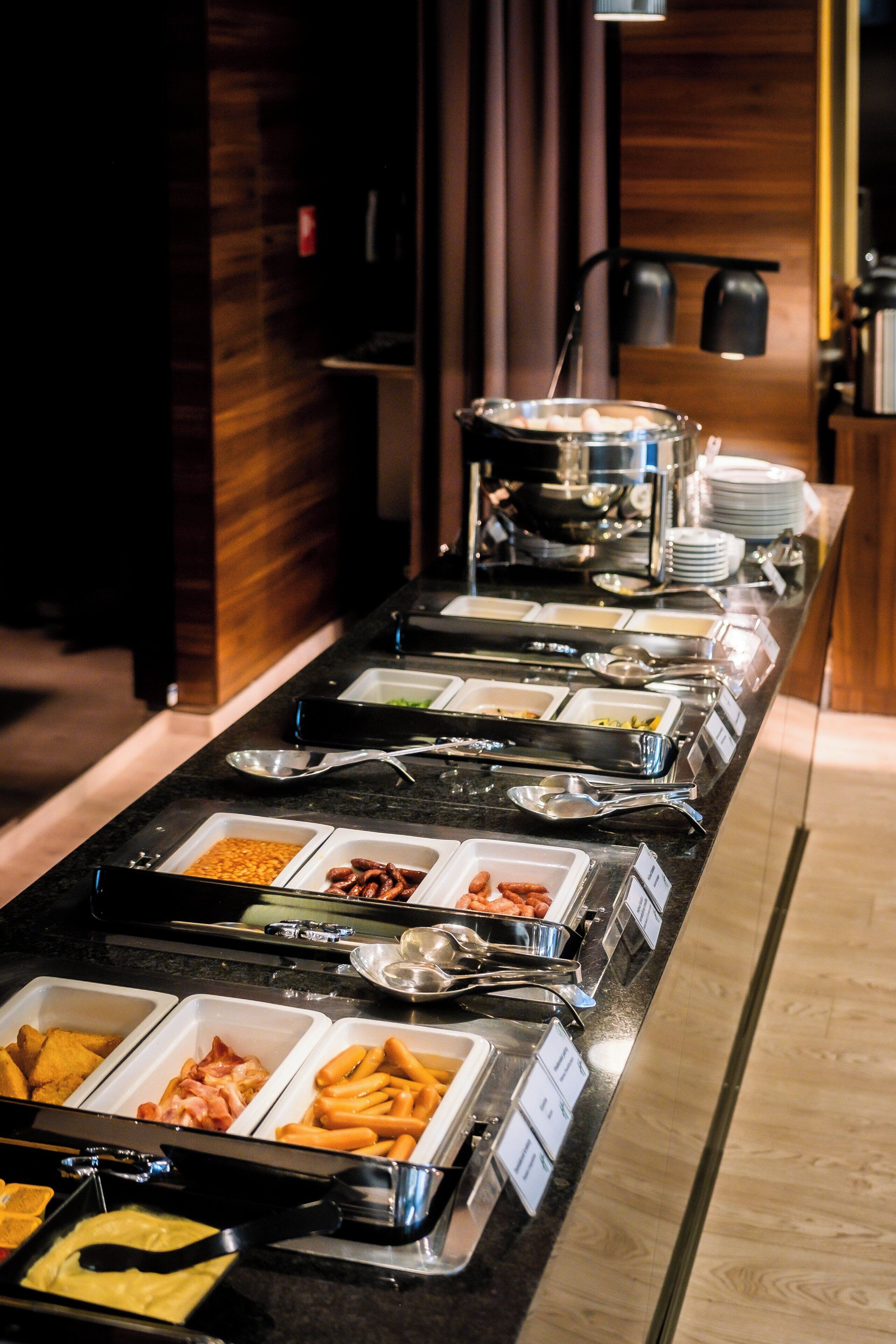 Buffet com diversos alimentos e utensílios de servir.